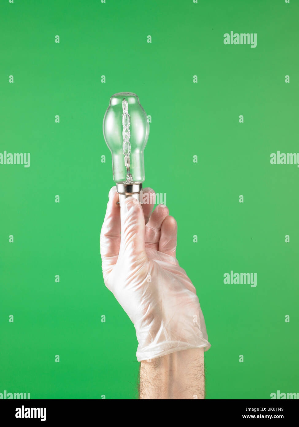 Gloved hand on green with light bulb Stock Photo - Alamy