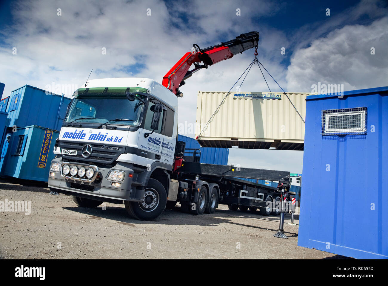 A truck or lorry fitted with a crane lifting ainto position in a site ...