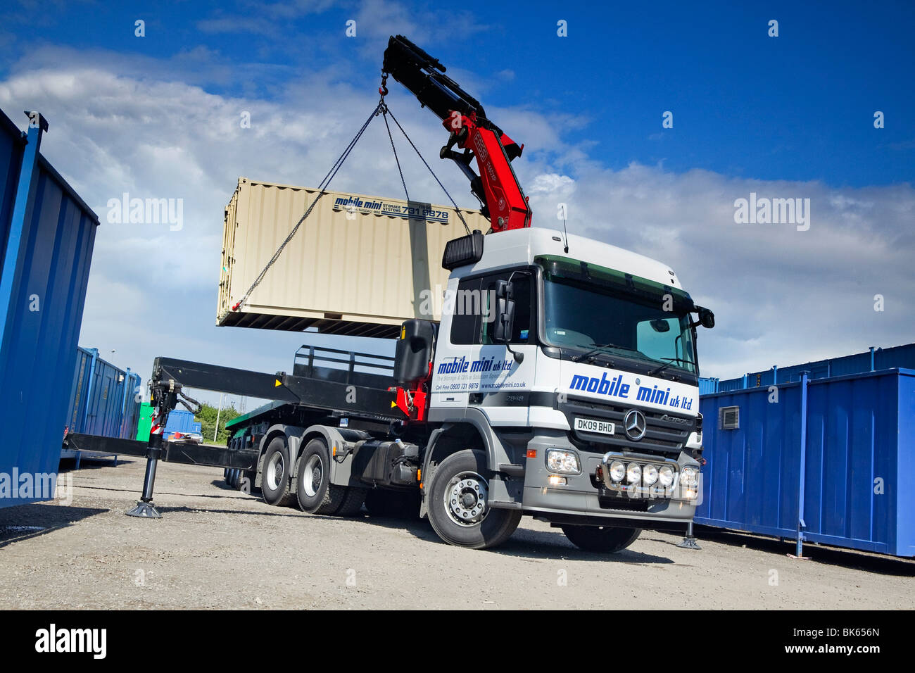 A truck or lorry fitted with a crane lifting ainto position in a site ...