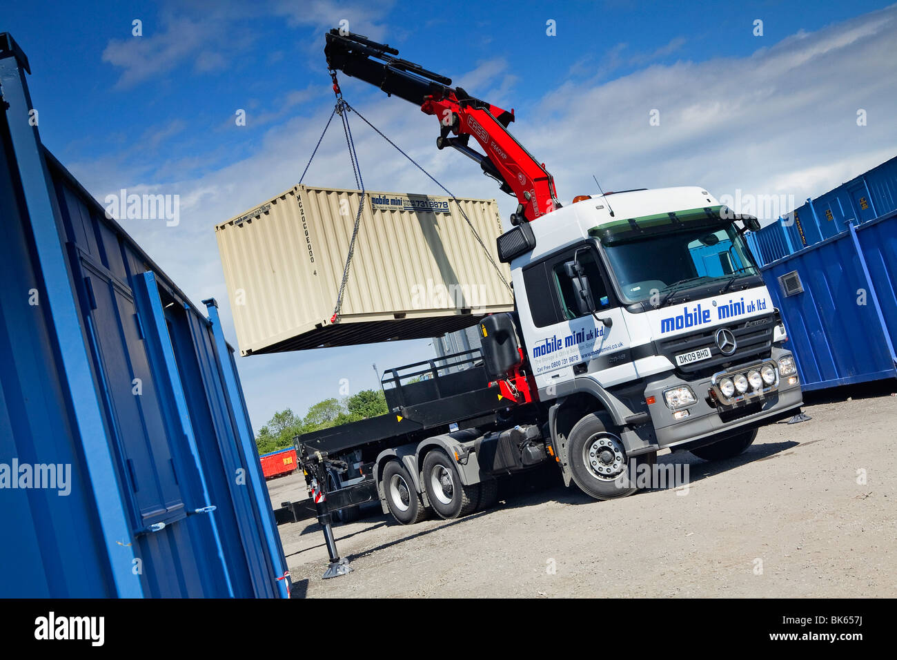 A truck or lorry fitted with a crane lifting ainto position in a site ...
