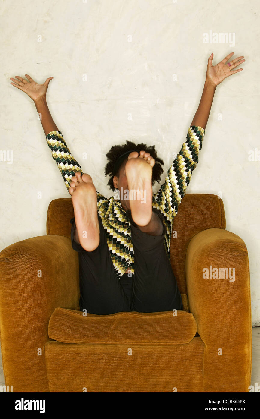Young woman sitting on a couch and looking excited Stock Photo - Alamy