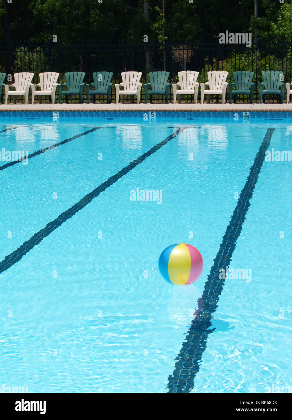A beach ball floating on the surface of a refreshing swimming pool in ...