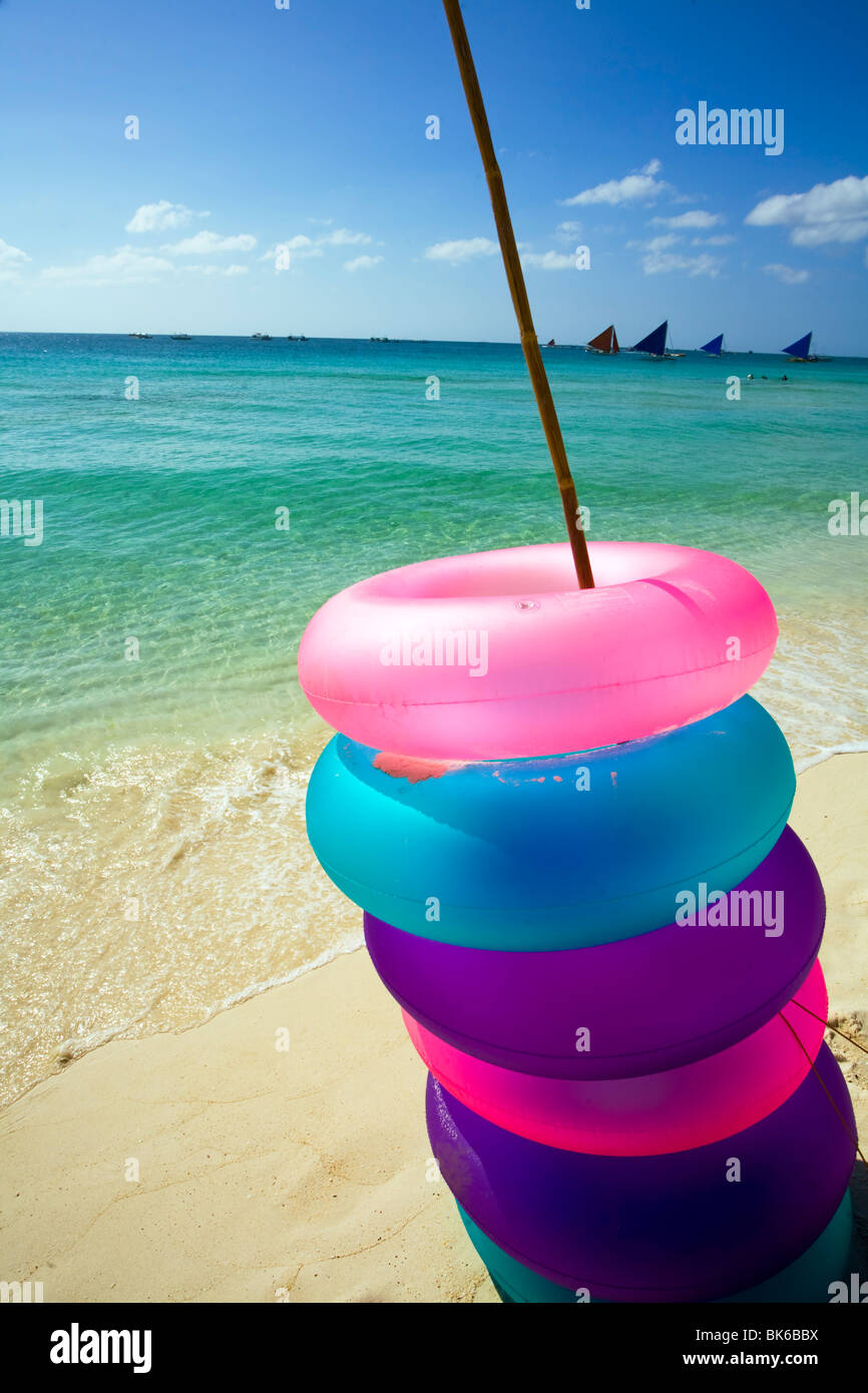 Colourful inflatable rings on a beach midday Stock Photo - Alamy