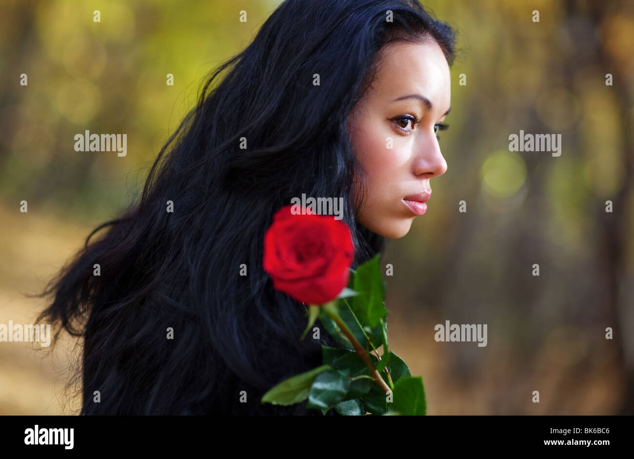 Young brunette woman with red rose portrait Stock Photo - Alamy