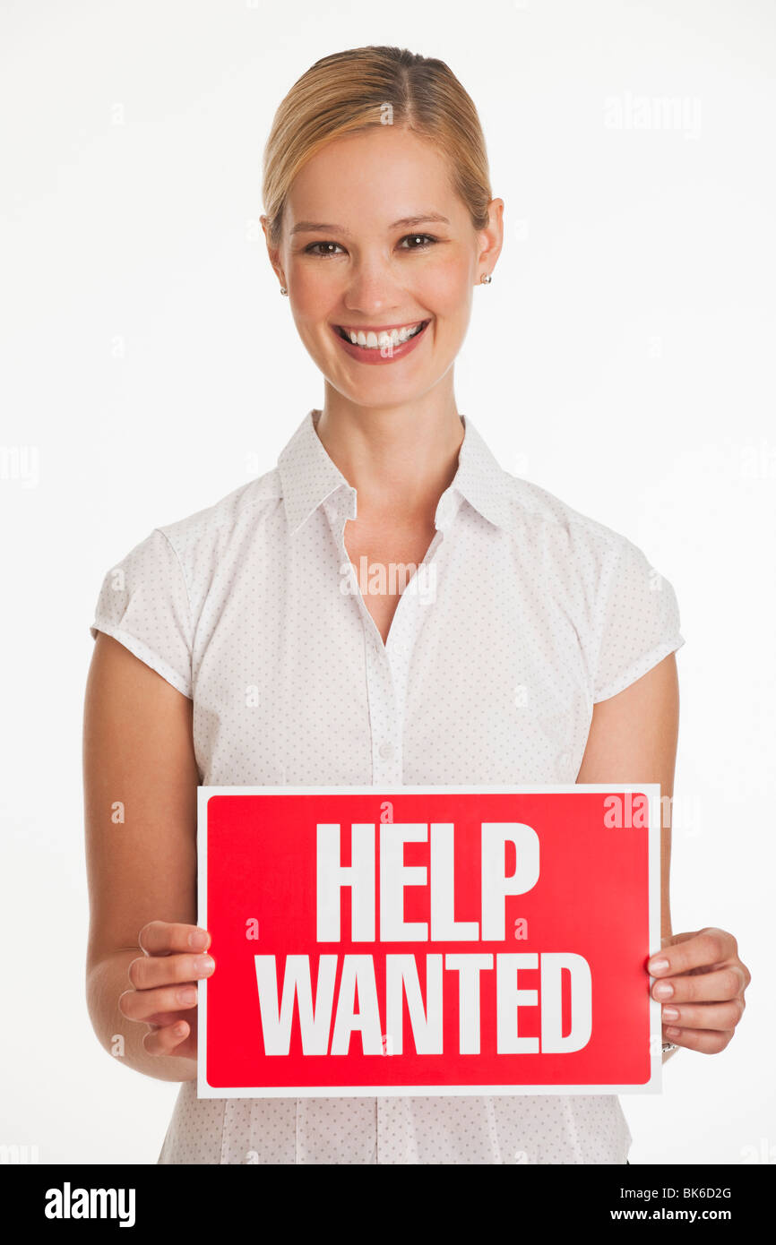 female small business owner holding up Help Wanted sign with white ...