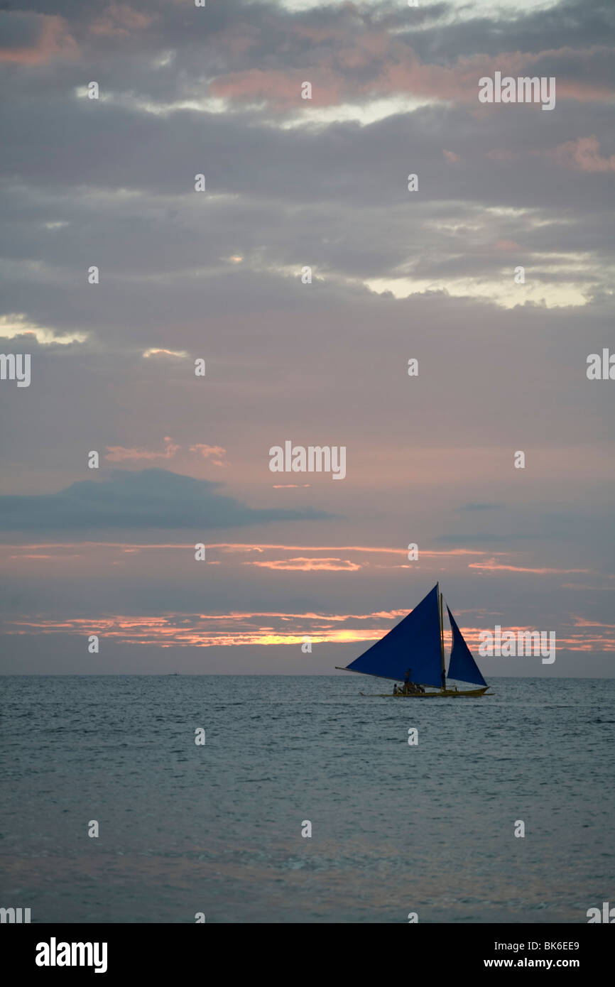 A distant sailboat at sunset Stock Photo - Alamy