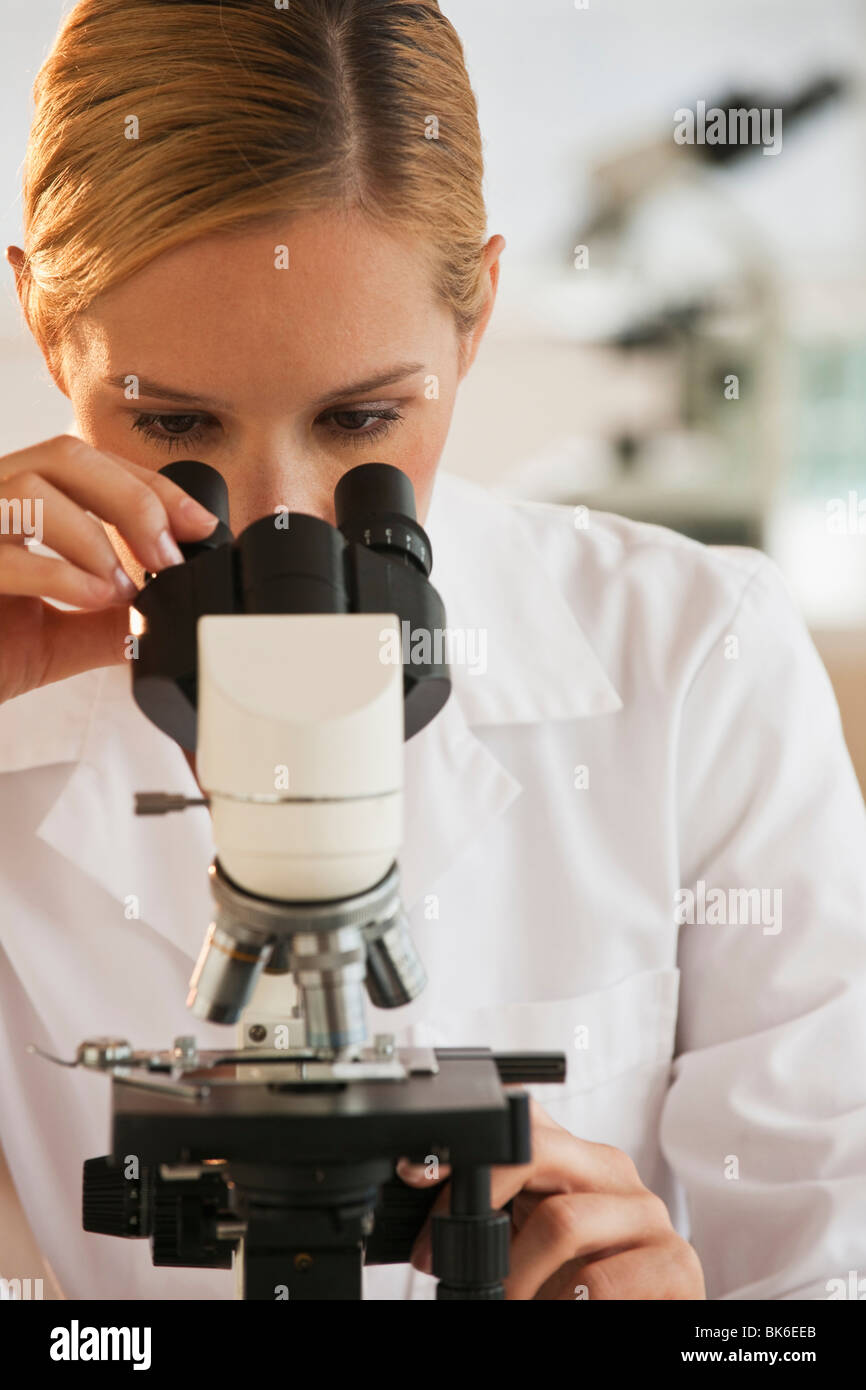 female scientist looking through microscope and doing research in lab ...