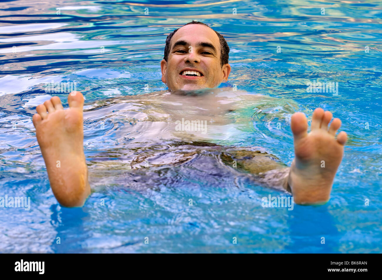 Portrait of a happy man in a swimming pool with feet up Stock Photo - Alamy