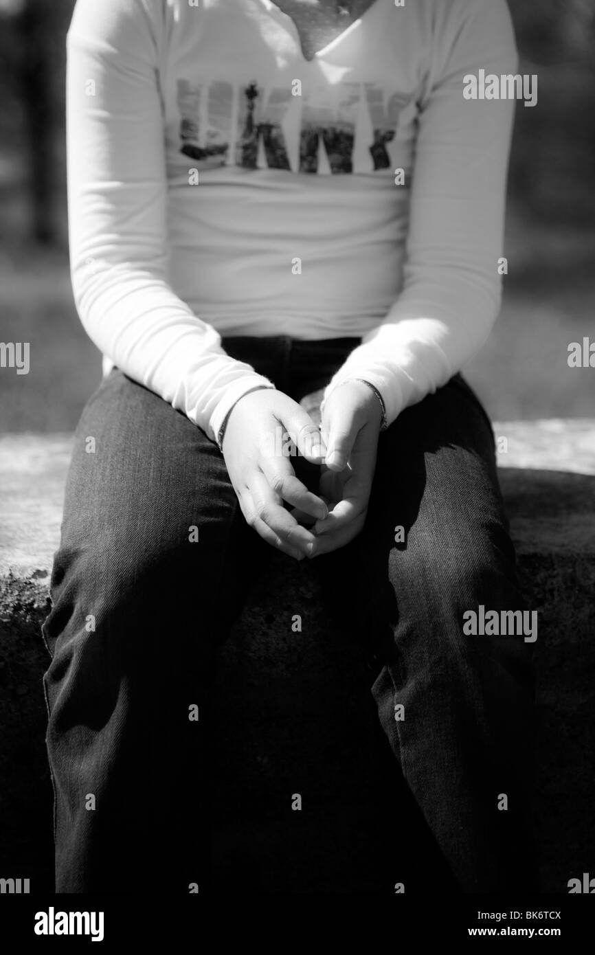 Loneliness. Young girl wearing sitting alone outdoor Stock Photo - Alamy