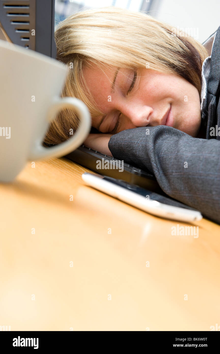 tired female office worker sleeping on desk Stock Photo - Alamy