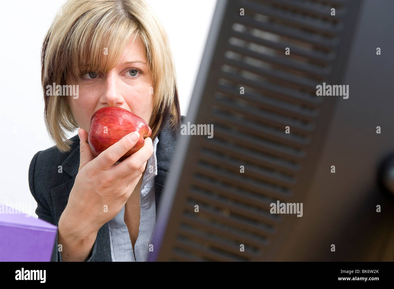 female office worker eating red apple in lunch break Stock Photo - Alamy