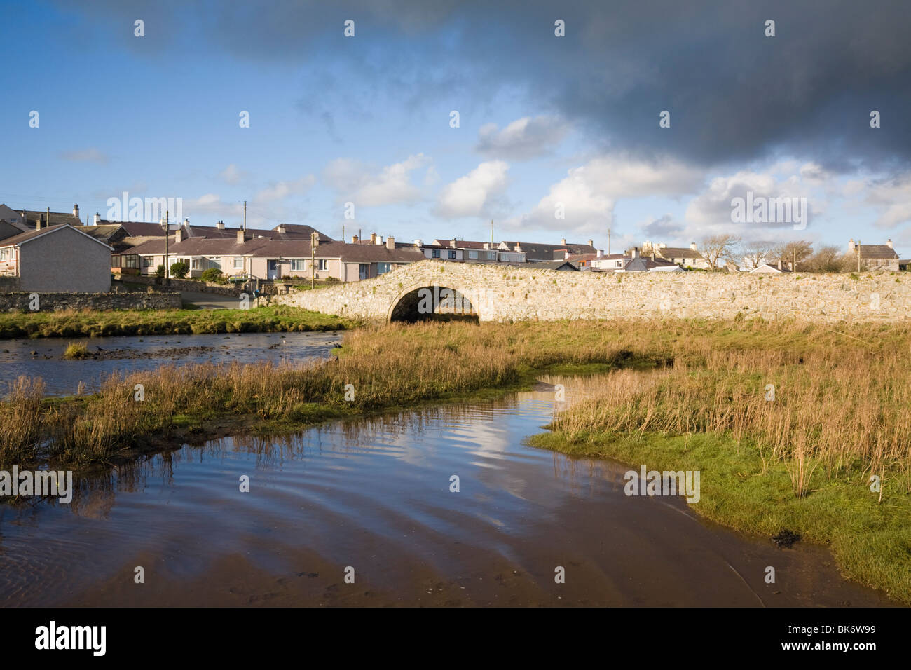 Salt marsh by tidal Afon Ffraw River estuary on coast with old bridge ...