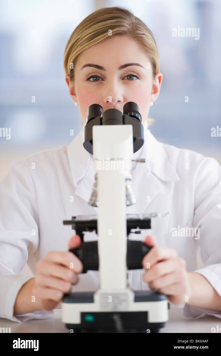 female scientist holding microscope and looking into camera Stock Photo ...