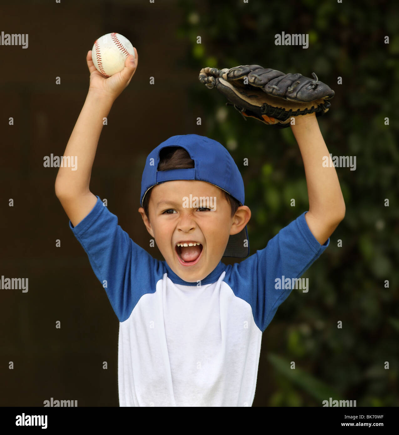 Young hispanic boy with baseball and glove celebrates on dark ...