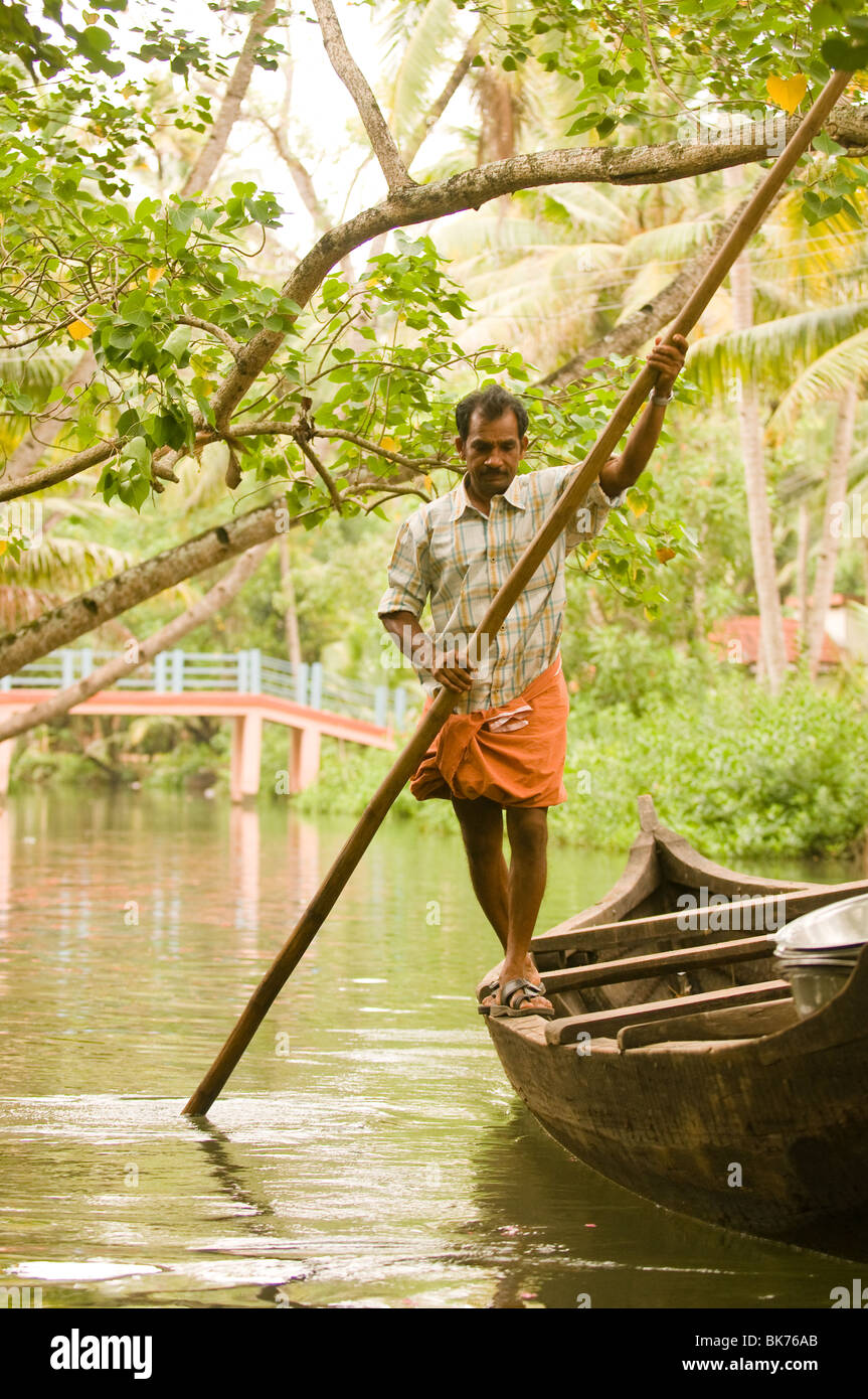 This is an image of an Indian man steering a boat through the jungle ...