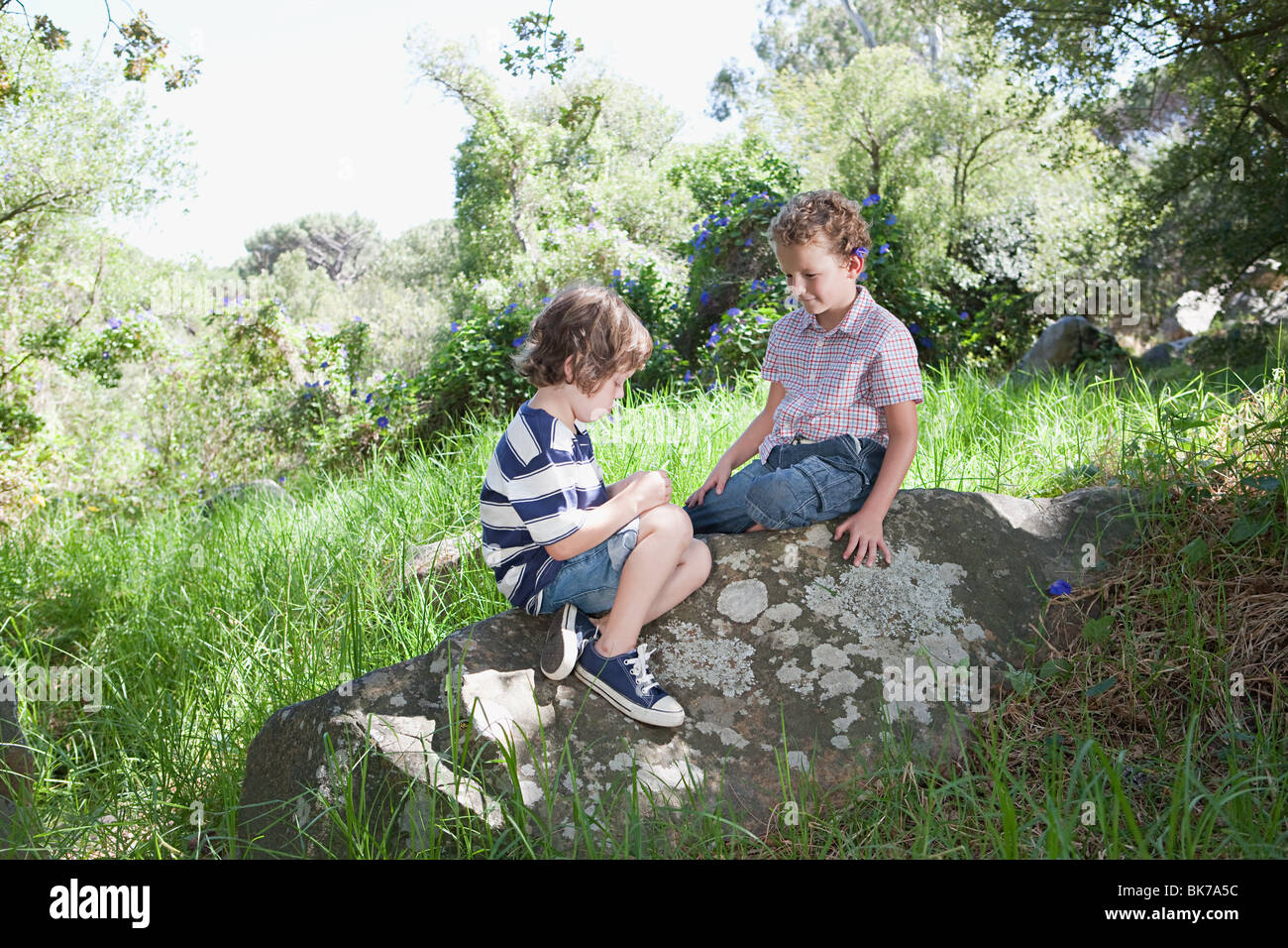 Two boys sitting on a rock Stock Photo - Alamy