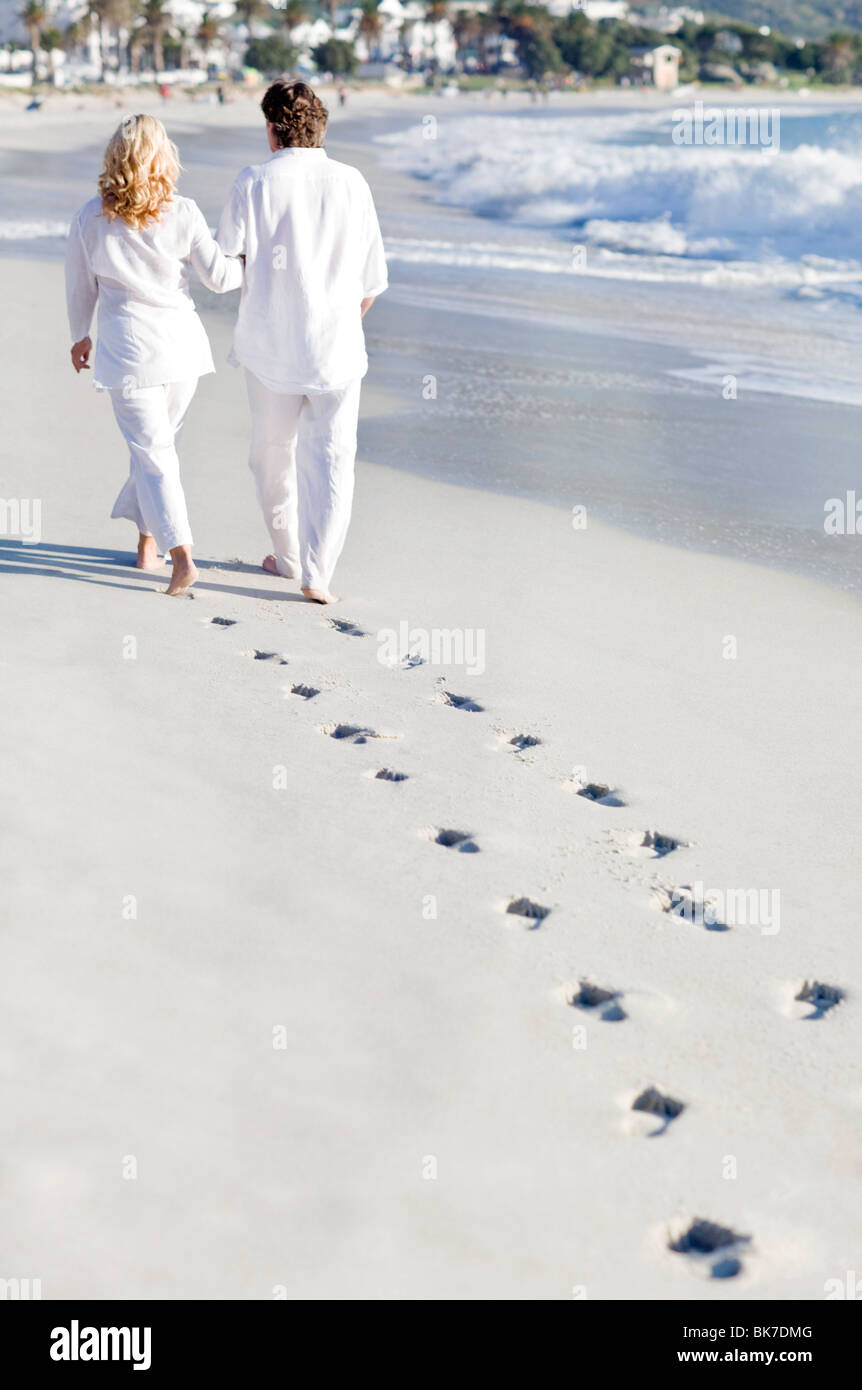 Couple walking along a beach Stock Photo - Alamy