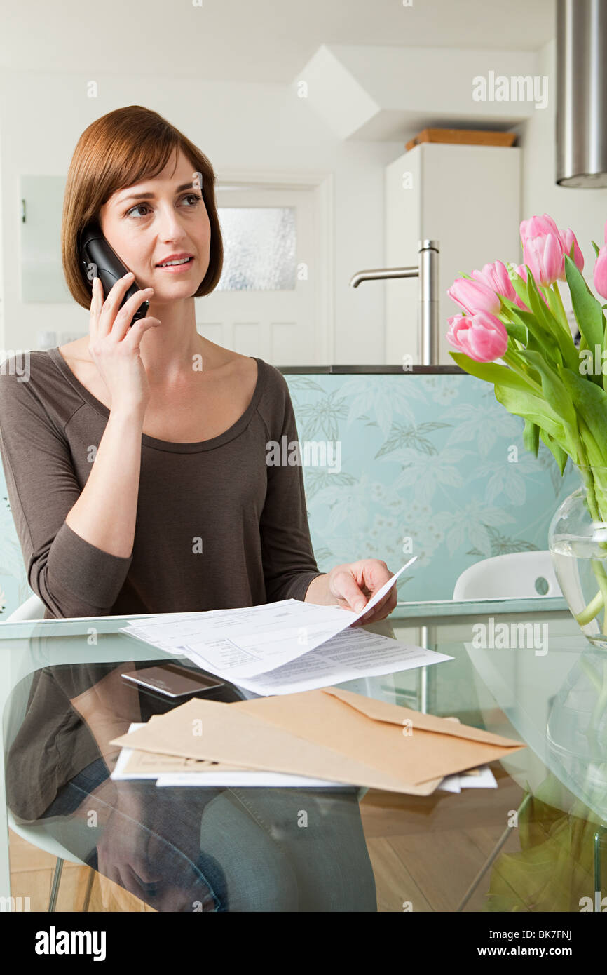 Woman on telephone with bills Stock Photo - Alamy