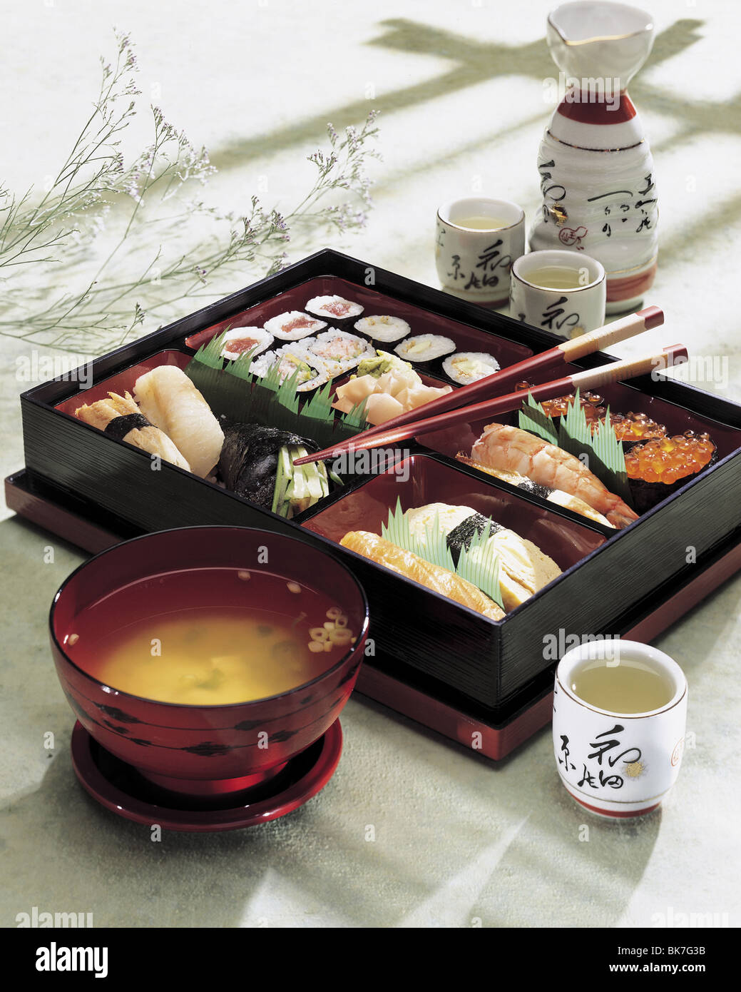 Japanese sushi box with soup and saki, chopsticks on a light green ...