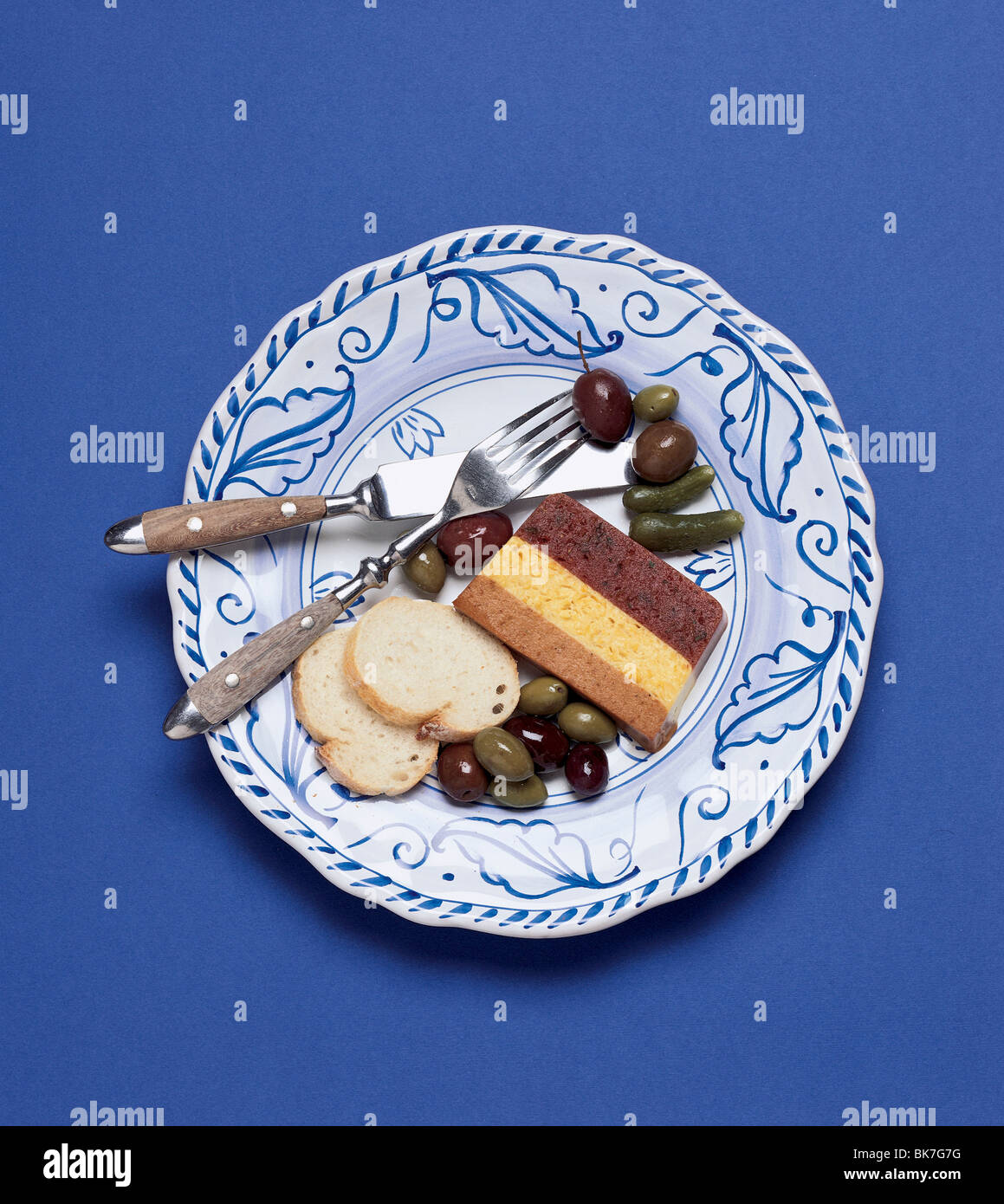 Tri-color pate with olives, corniche, and bread on a blue and white ...