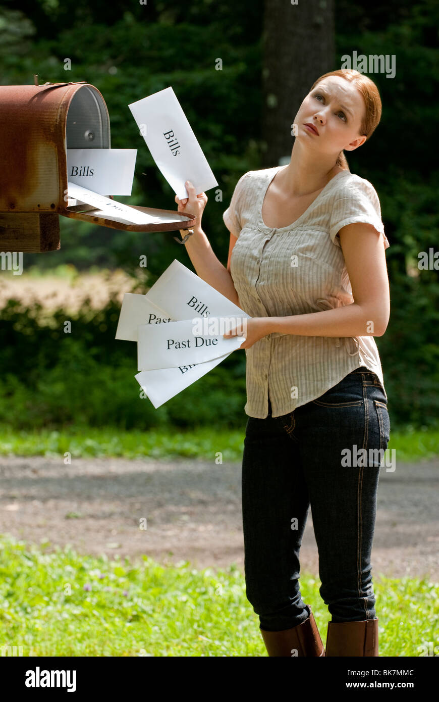 Young woman receiving bills in her mailbox Stock Photo - Alamy