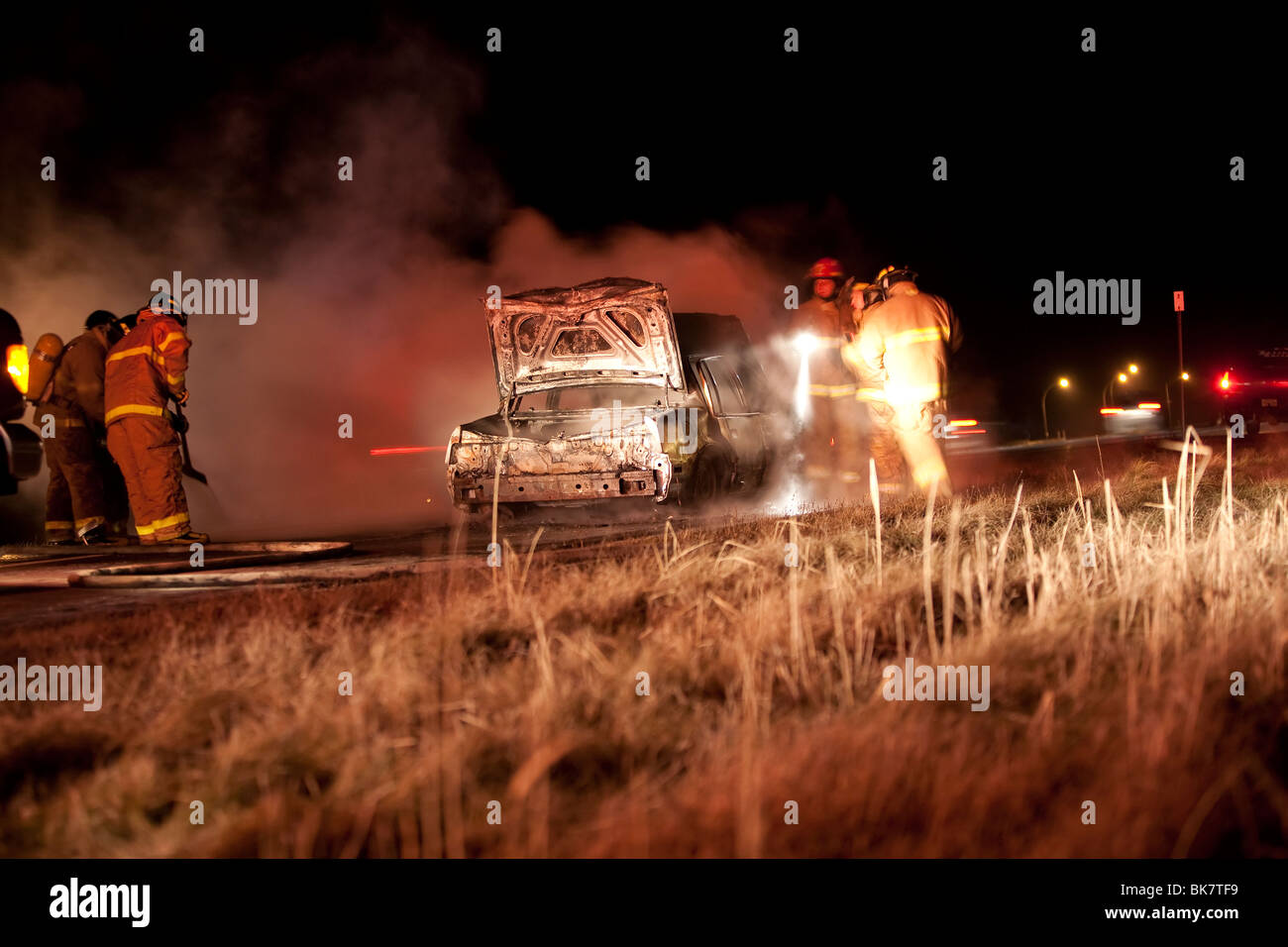 Firefighters at the scene of an accident where a car burns Stock Photo ...