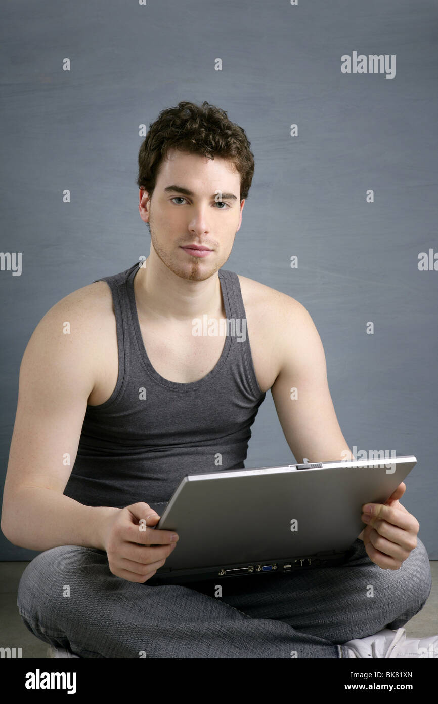 handsome student young man sit working on laptop over gray background ...
