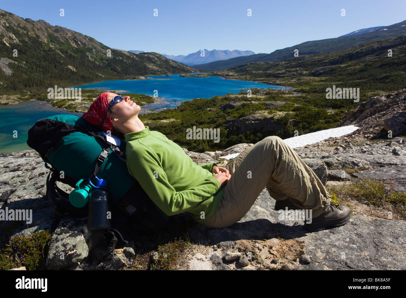 Young woman, hiker, backpacker, sitting on a rock, resting, enjoying ...