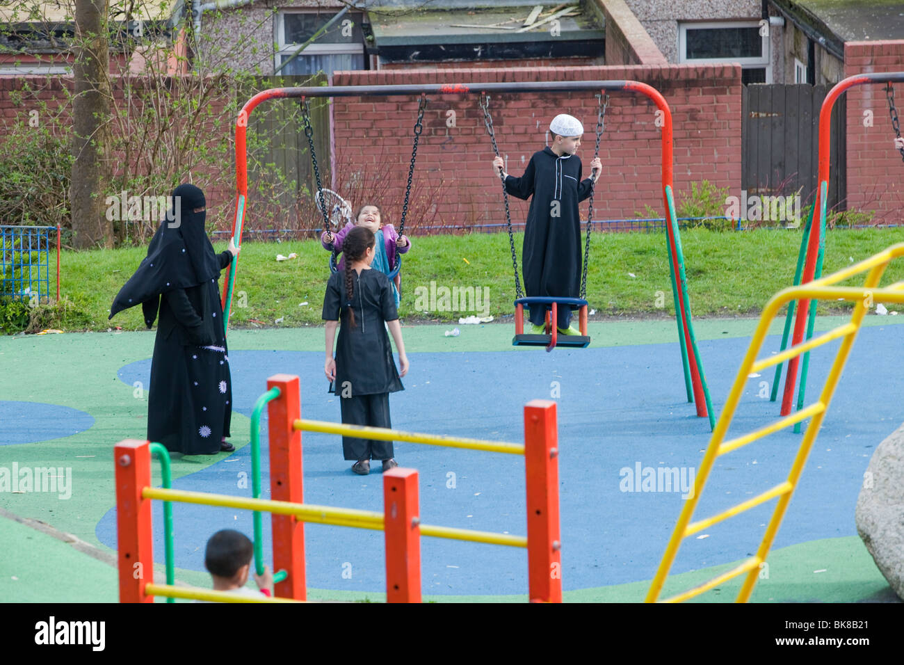 Muslims including a women in a burkha in a playground in a muslim area ...