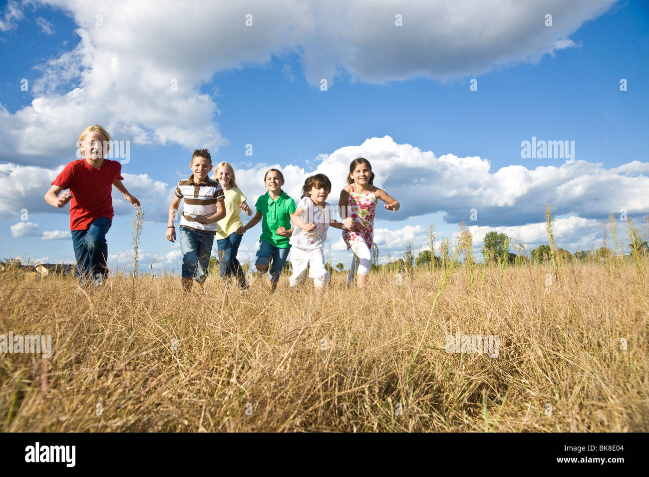 A group of laughing children running through the grass Stock Photo - Alamy