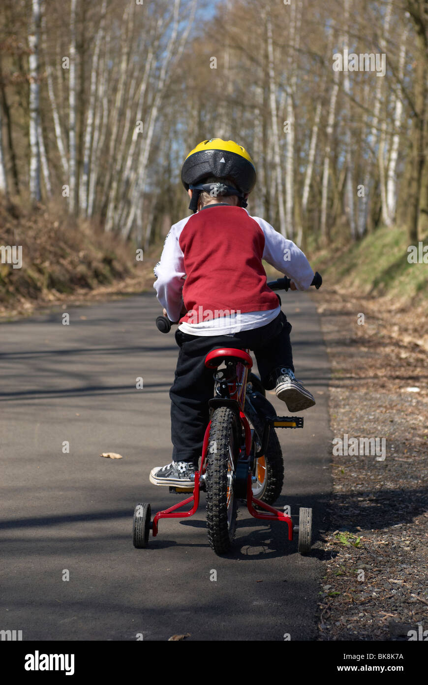 Boy Learning to Ride Bicycle with stabilizing wheel bike Stock Photo ...