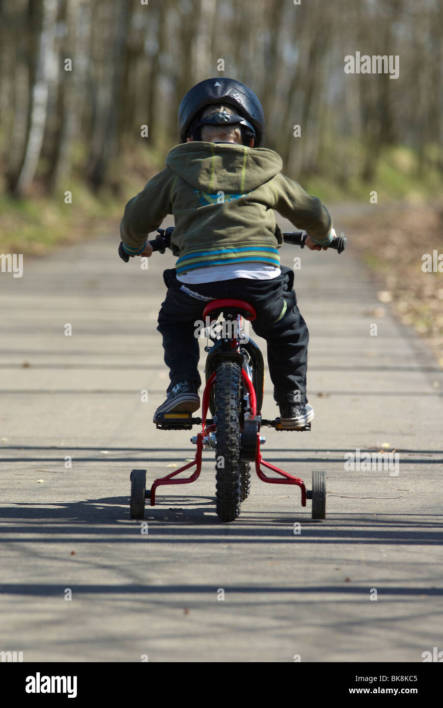 Boy Learning to Ride Bicycle with stabilizing wheel bike Stock Photo ...