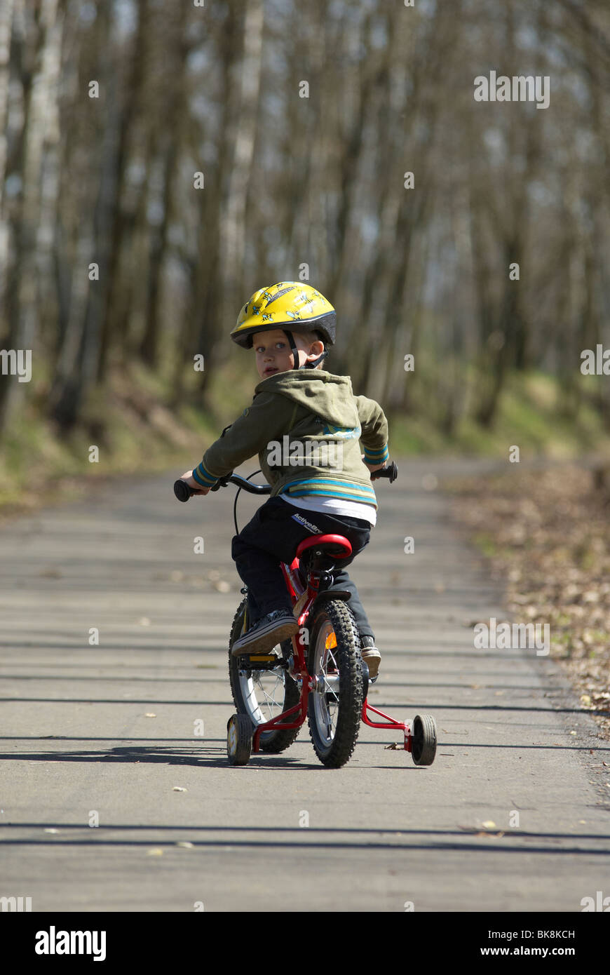 Boy Learning to Ride Bicycle with stabilizing wheel bike Stock Photo ...