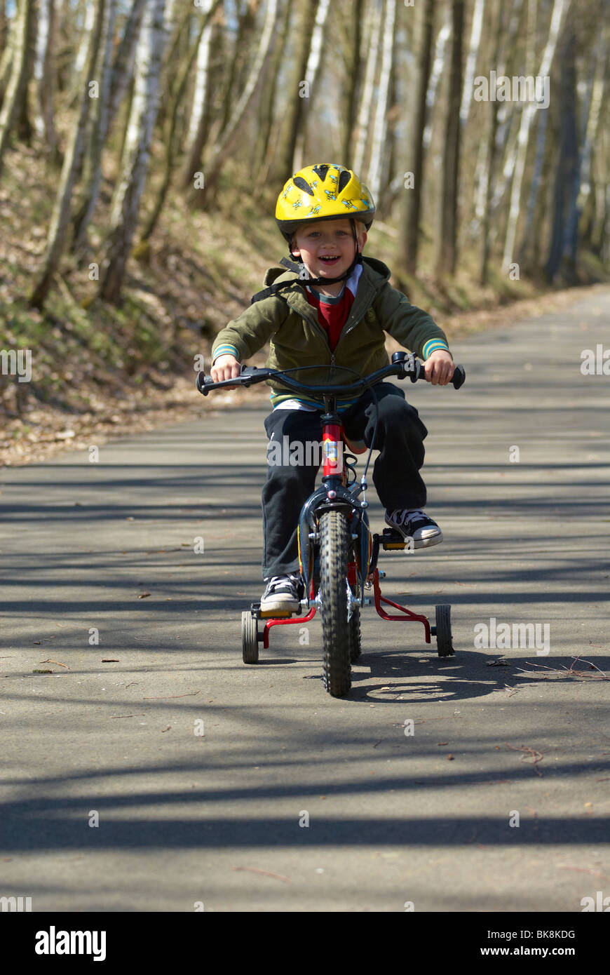 Boy Learning to Ride Bicycle with stabilizing wheel bike Stock Photo ...