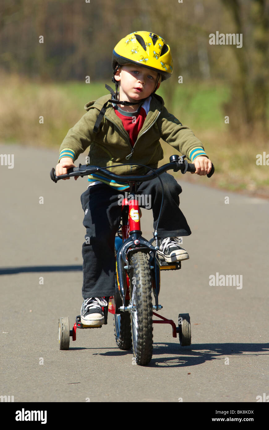 Boy Learning to Ride Bicycle with stabilizing wheel bike Stock Photo ...