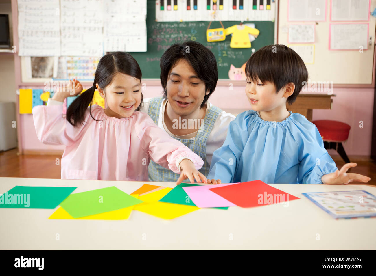 Kindergarten Teacher and Children Playing Origami Stock Photo - Alamy