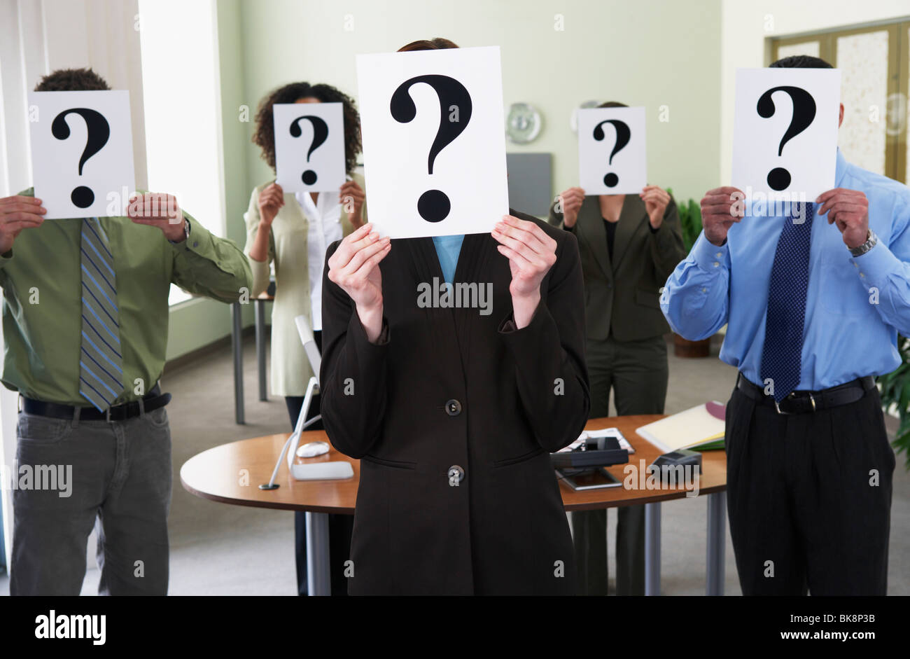 Business executives holding question mark cards in front their faces ...