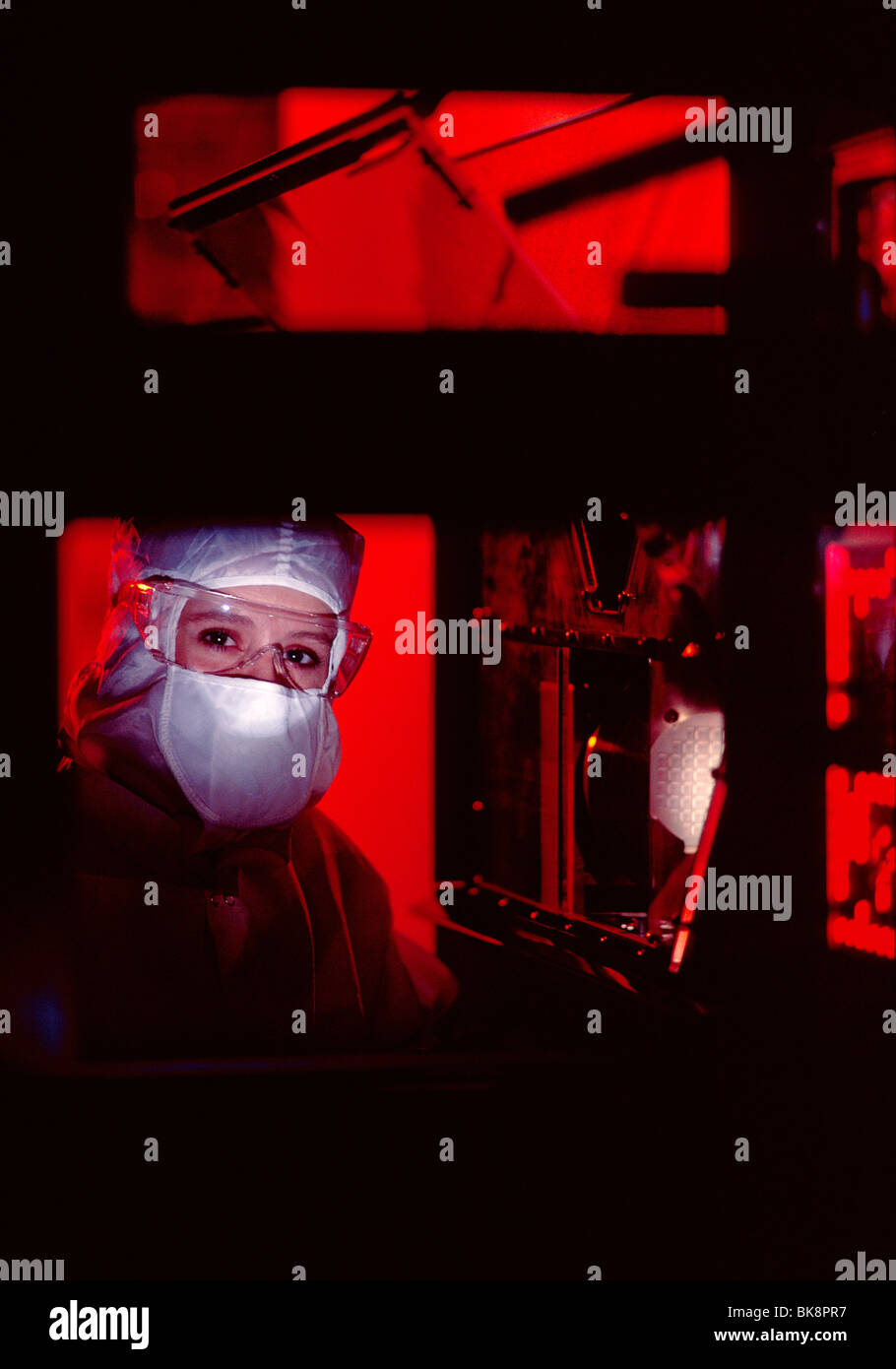Technician inspecting silicon wafers in a clean room environment used ...