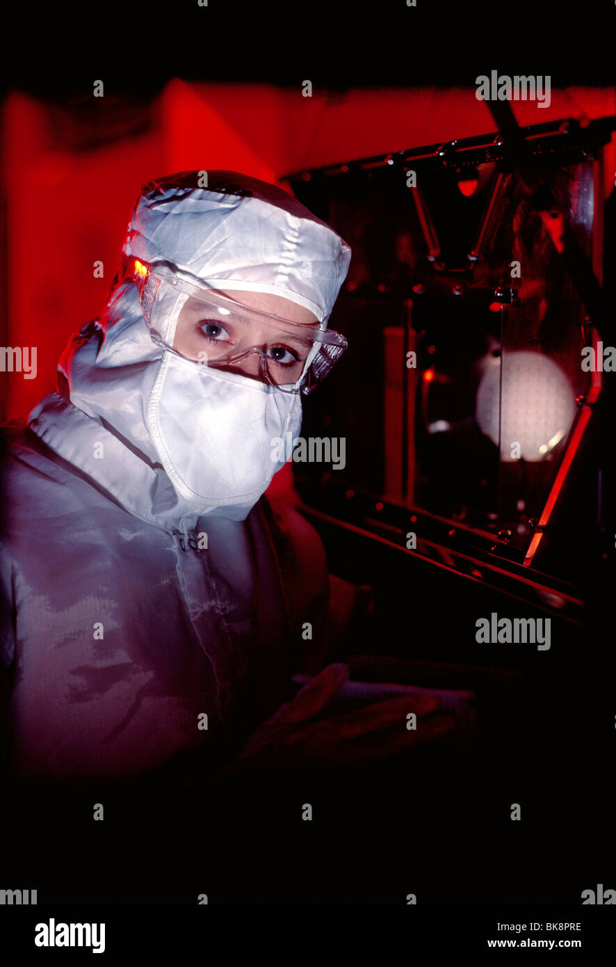 Technician inspecting silicon wafers in a clean room environment used ...