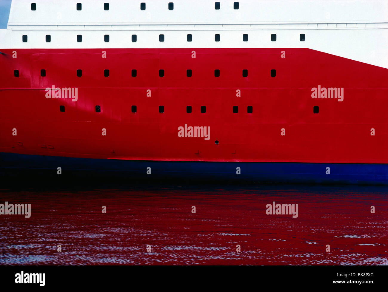 Close up of the hull and portholes of a red, white and blue ship in a ...