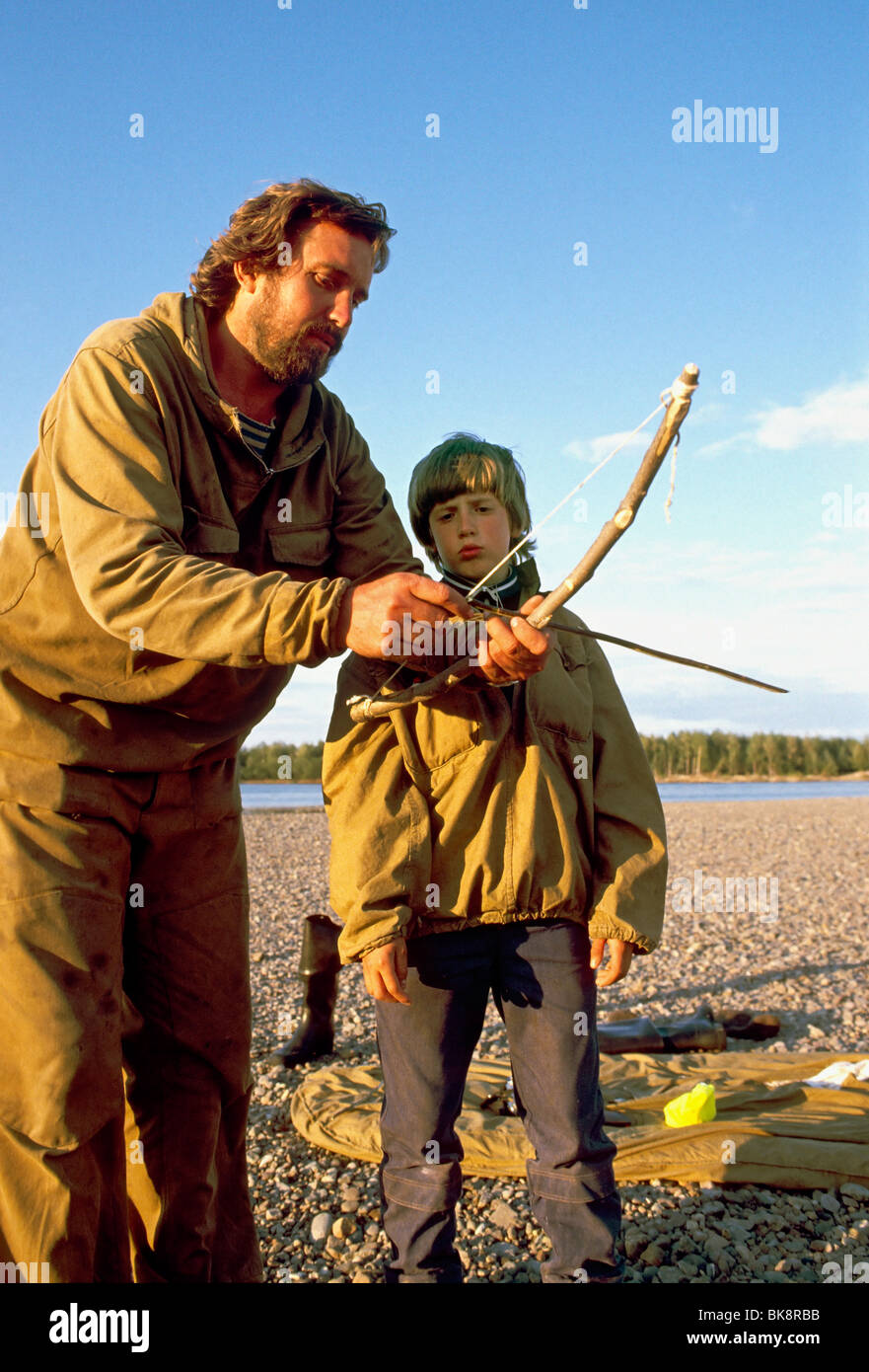 Russian river guide teaching his son to shoot a bow and arrow, Chukchi ...