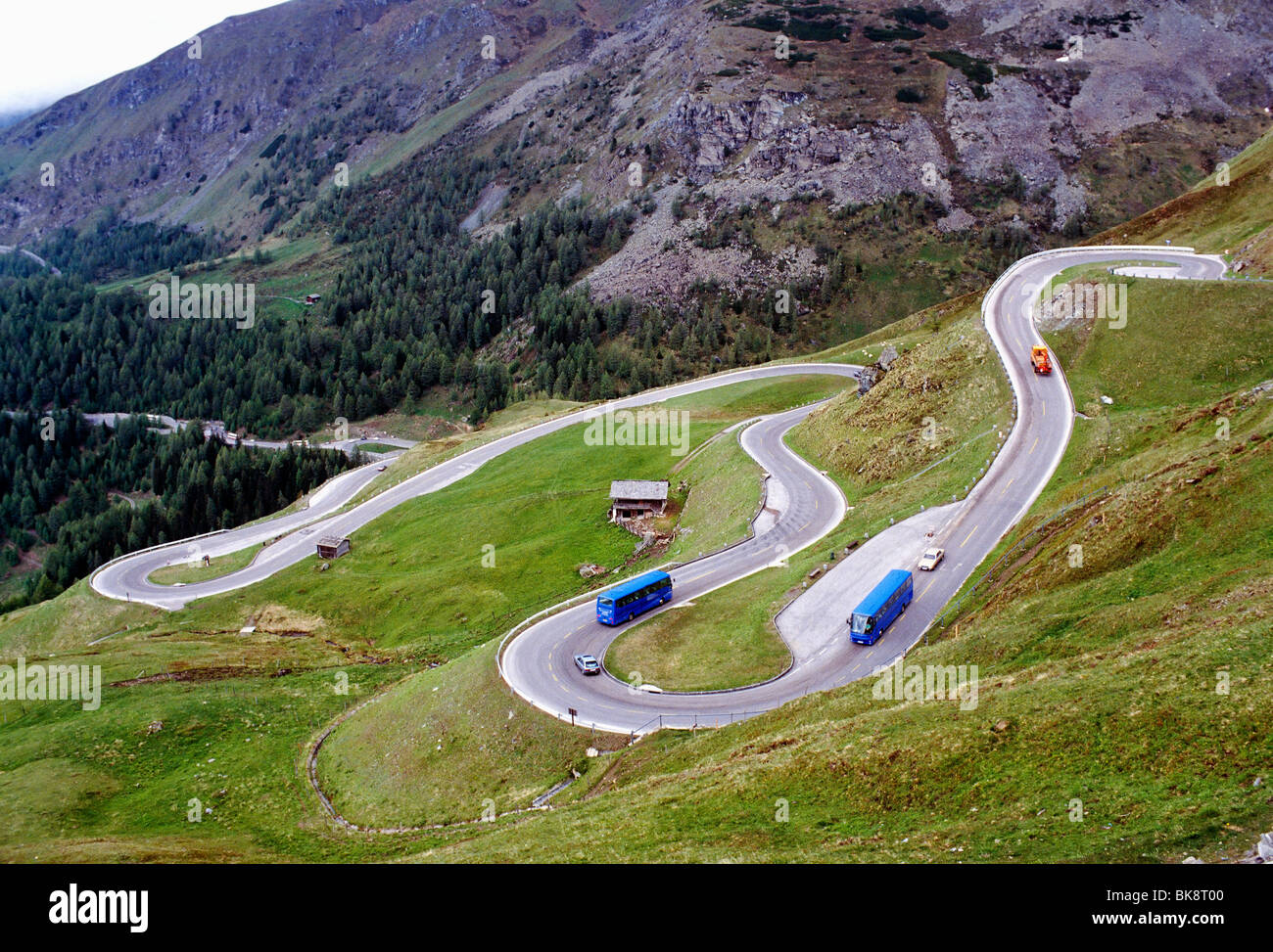 Cars and tour buses drive around switchback curves on a mountainous ...