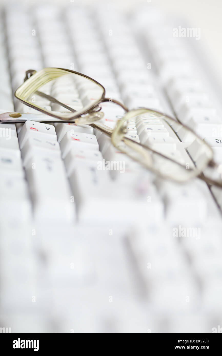 Spectacles are on the computer keyboard - poor eyesight Stock Photo - Alamy