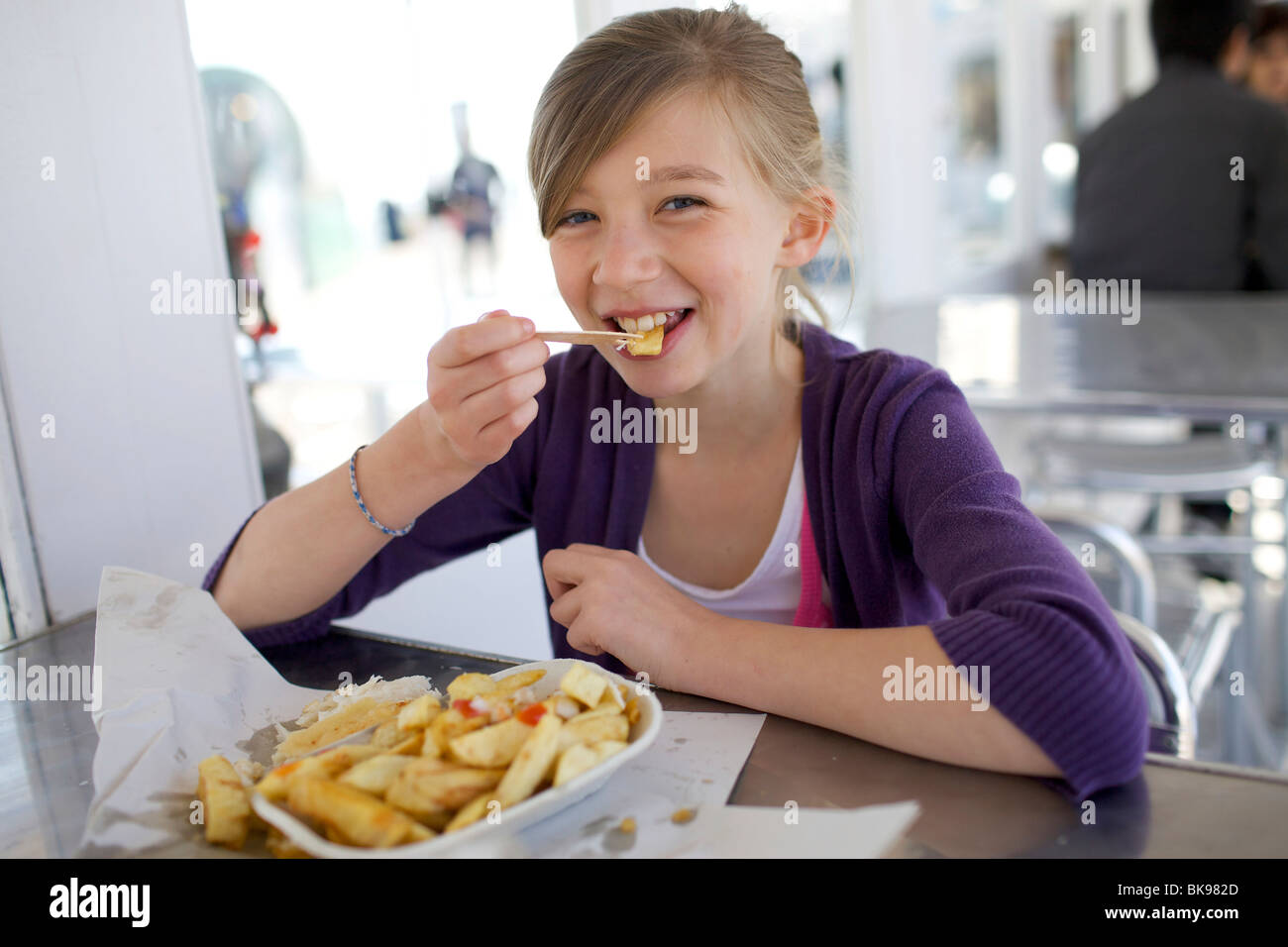 Young girl eating fish and chips on a seaside pier Stock Photo - Alamy
