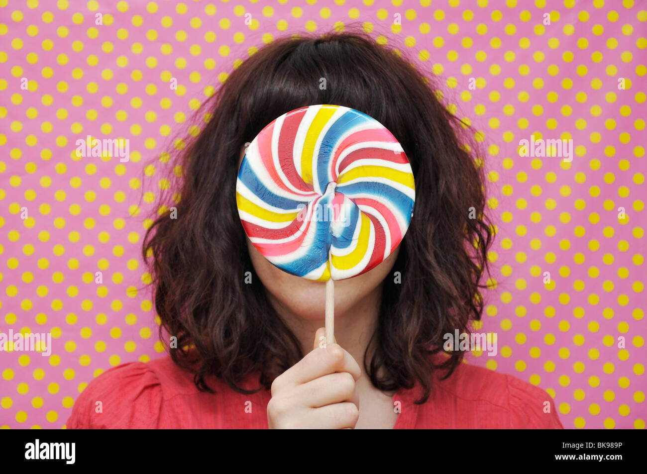 Young woman holding lollipop in front of face Stock Photo - Alamy