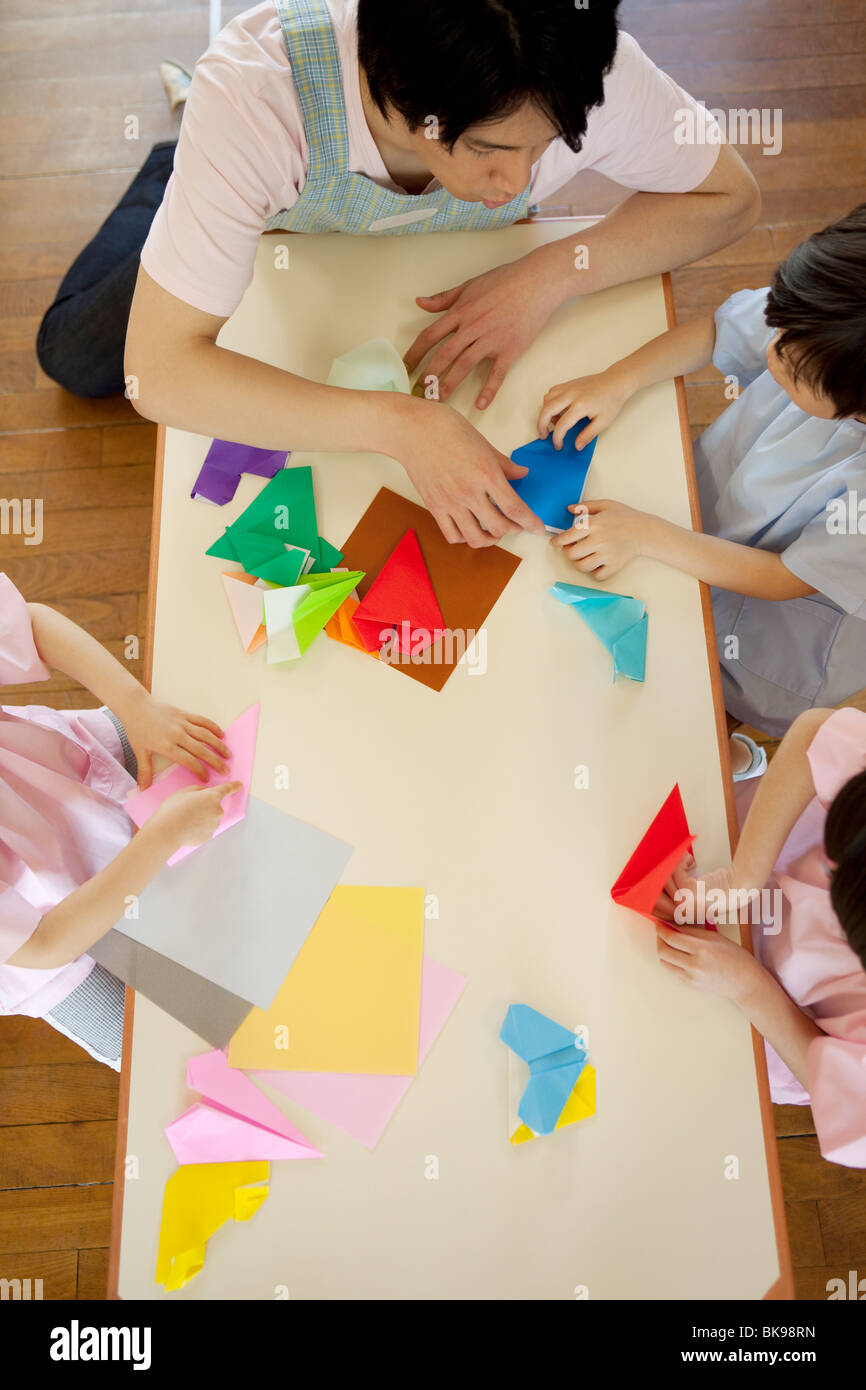 Kindergarten Teacher and Children Playing Origami Stock Photo - Alamy