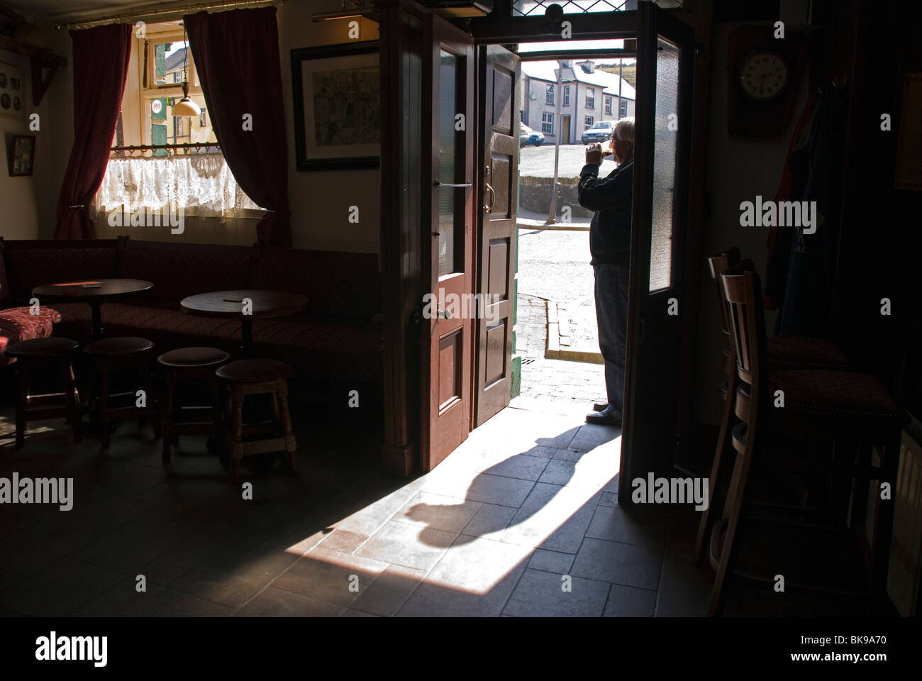 Man drinking a pint of Guinness in the doorway of a Donegal Irish bar ...