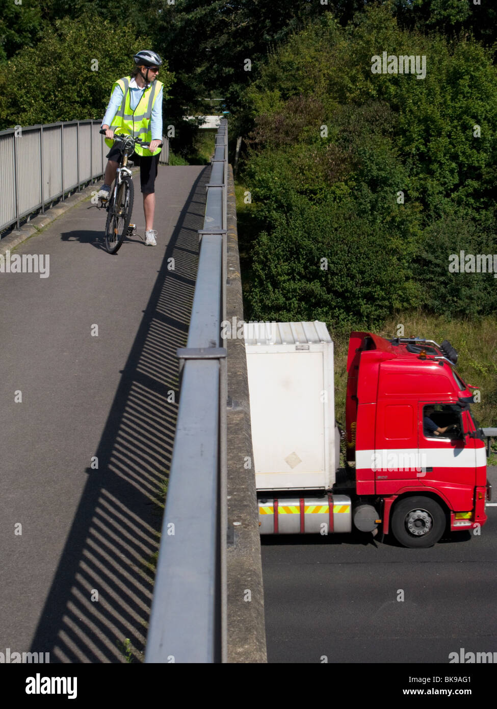 Cyclist on a pedestrian / cycle / footbridge looks down on lorry ...