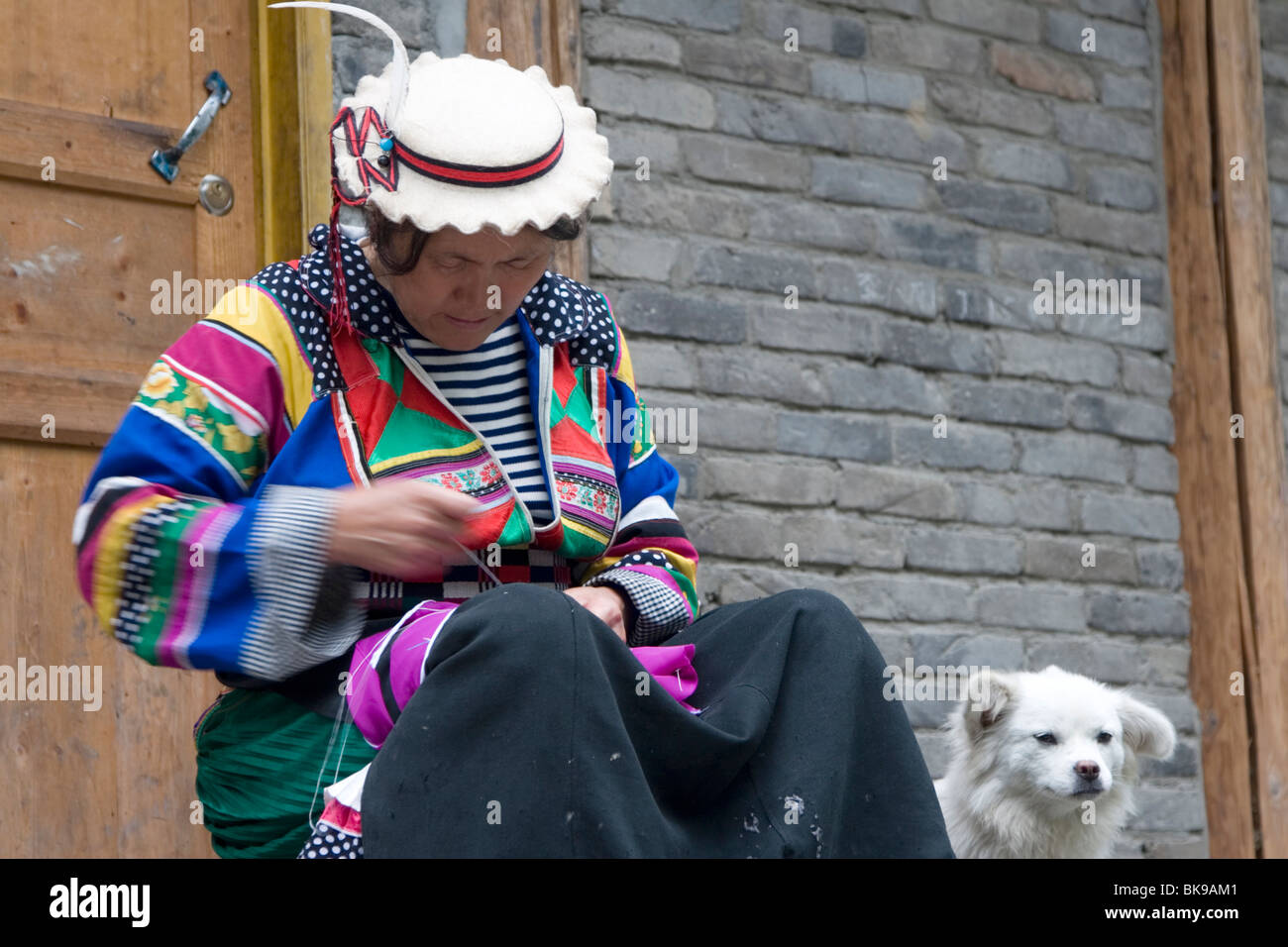 A woman of the Baima ethnic group sewing clothes manually outside her ...