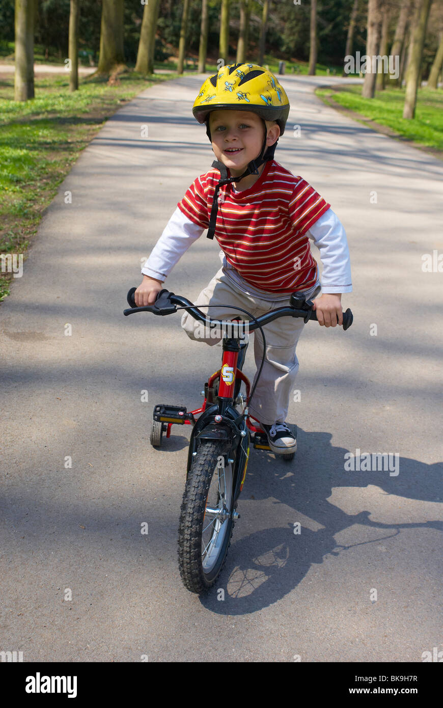 Boy Learning to Ride Bicycle with stabilizing wheel bike Stock Photo ...